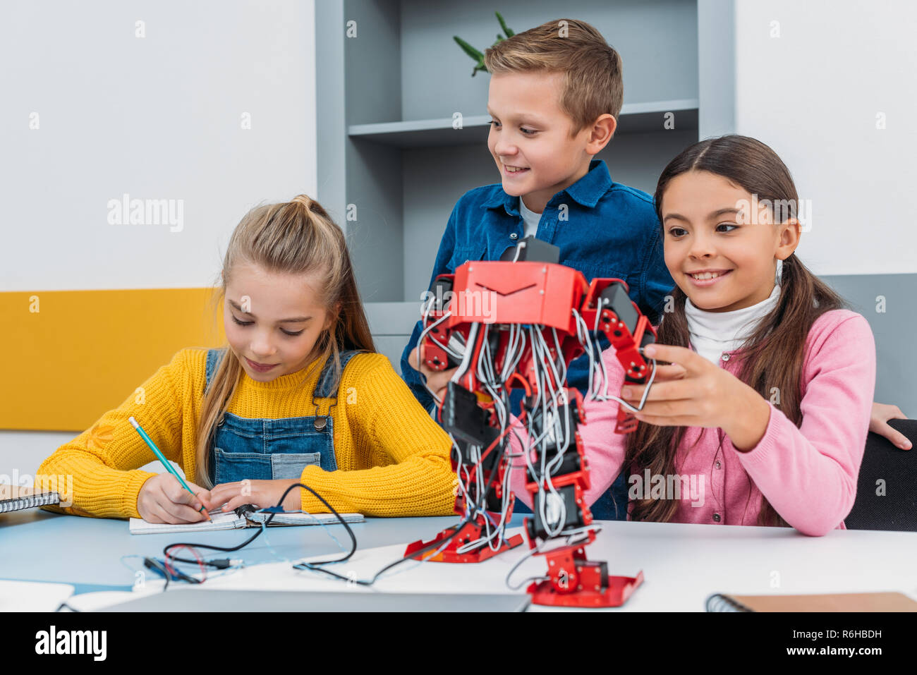 smiling schoolchildren making red robot in stem education class Stock ...