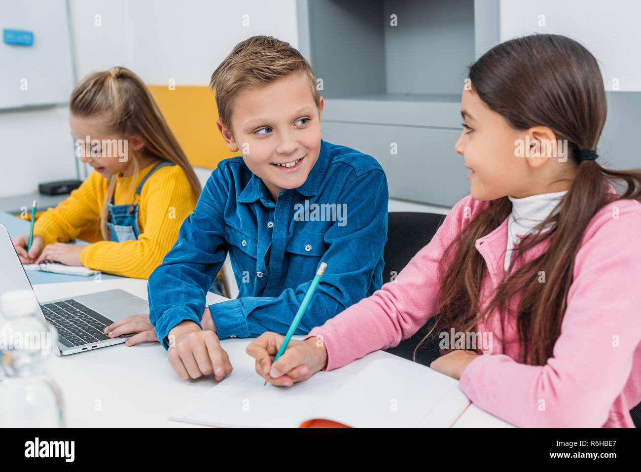 smiling children sitting at desk and in modern classroom Stock Photo ...