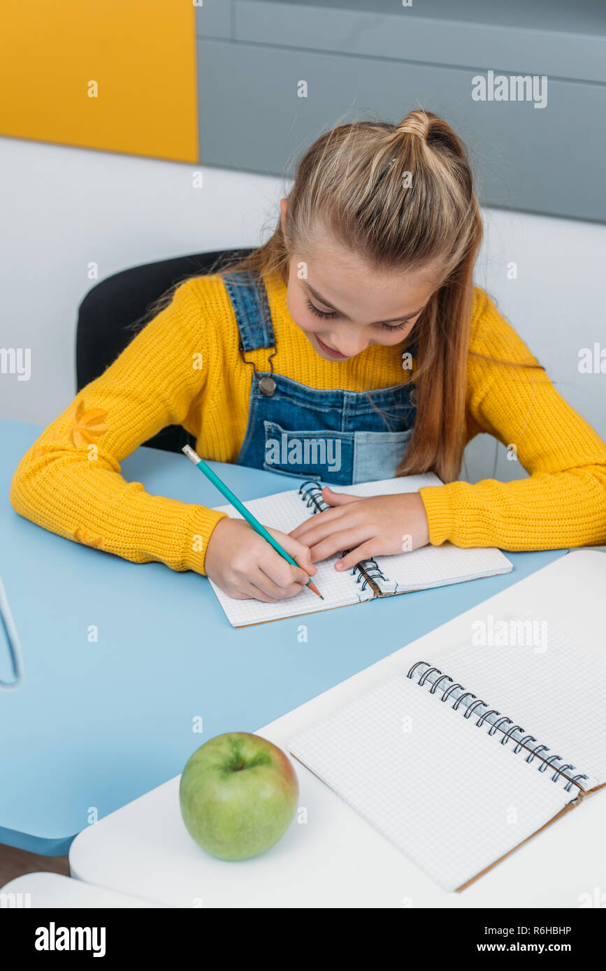 schoolkid writing in notepad during class Stock Photo - Alamy