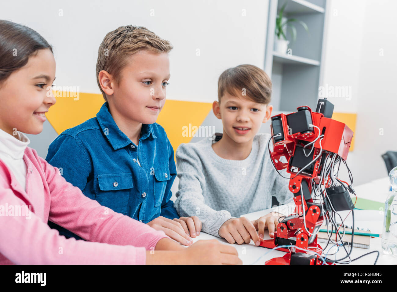 smiling schoolchildren looking at red plastic robot in classroom Stock ...