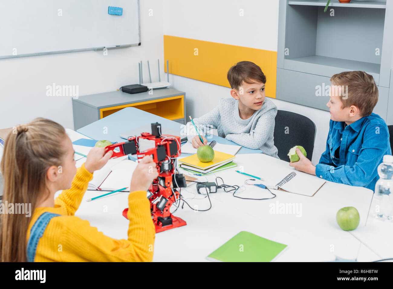 schoolchildren programming robot together and eating apples during STEM ...