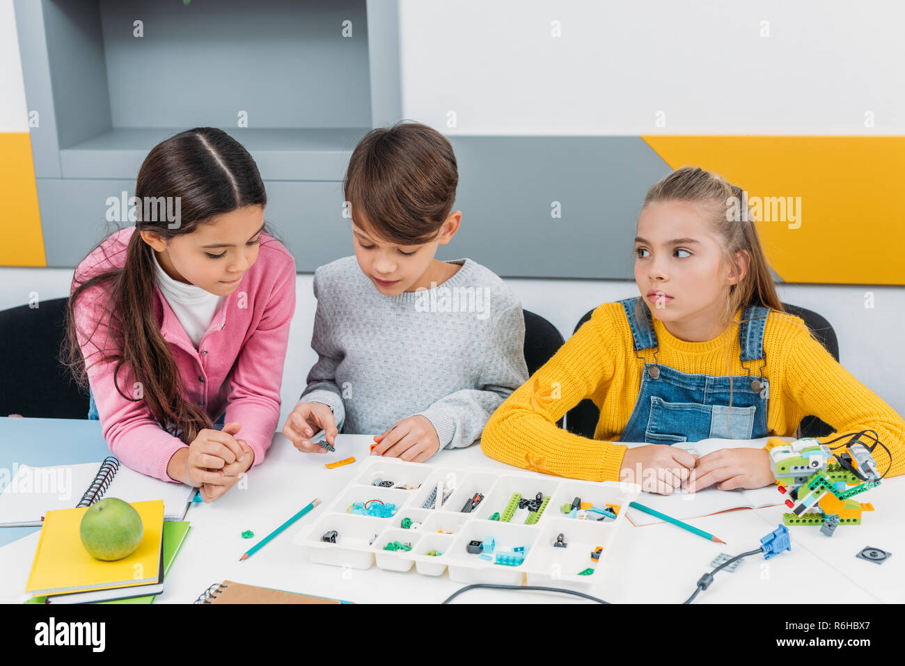 concentrated schoolchildren constructing robot with details during STEM ...