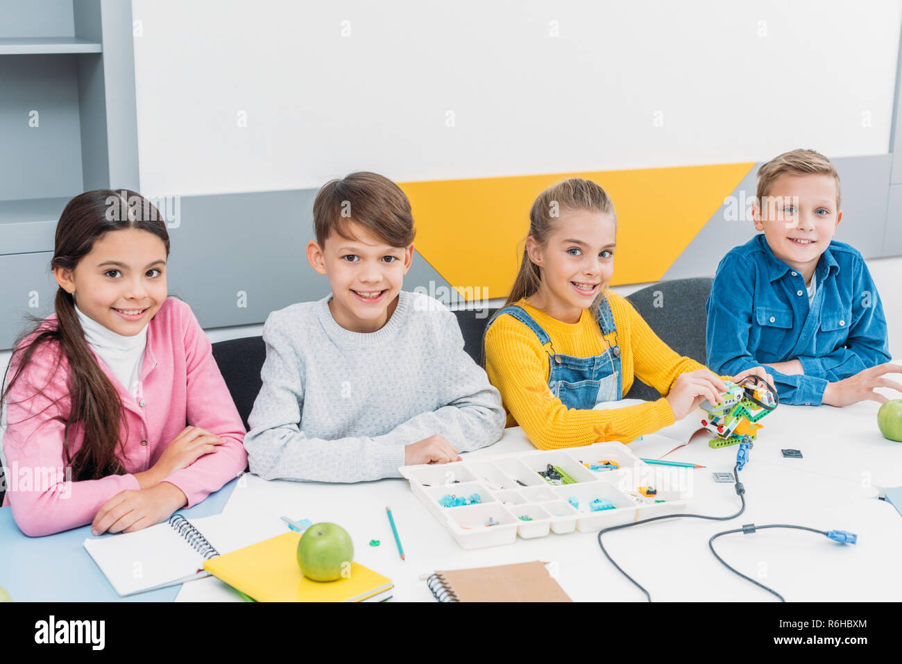 happy classmates at desk looking at camera and working in STEM ...