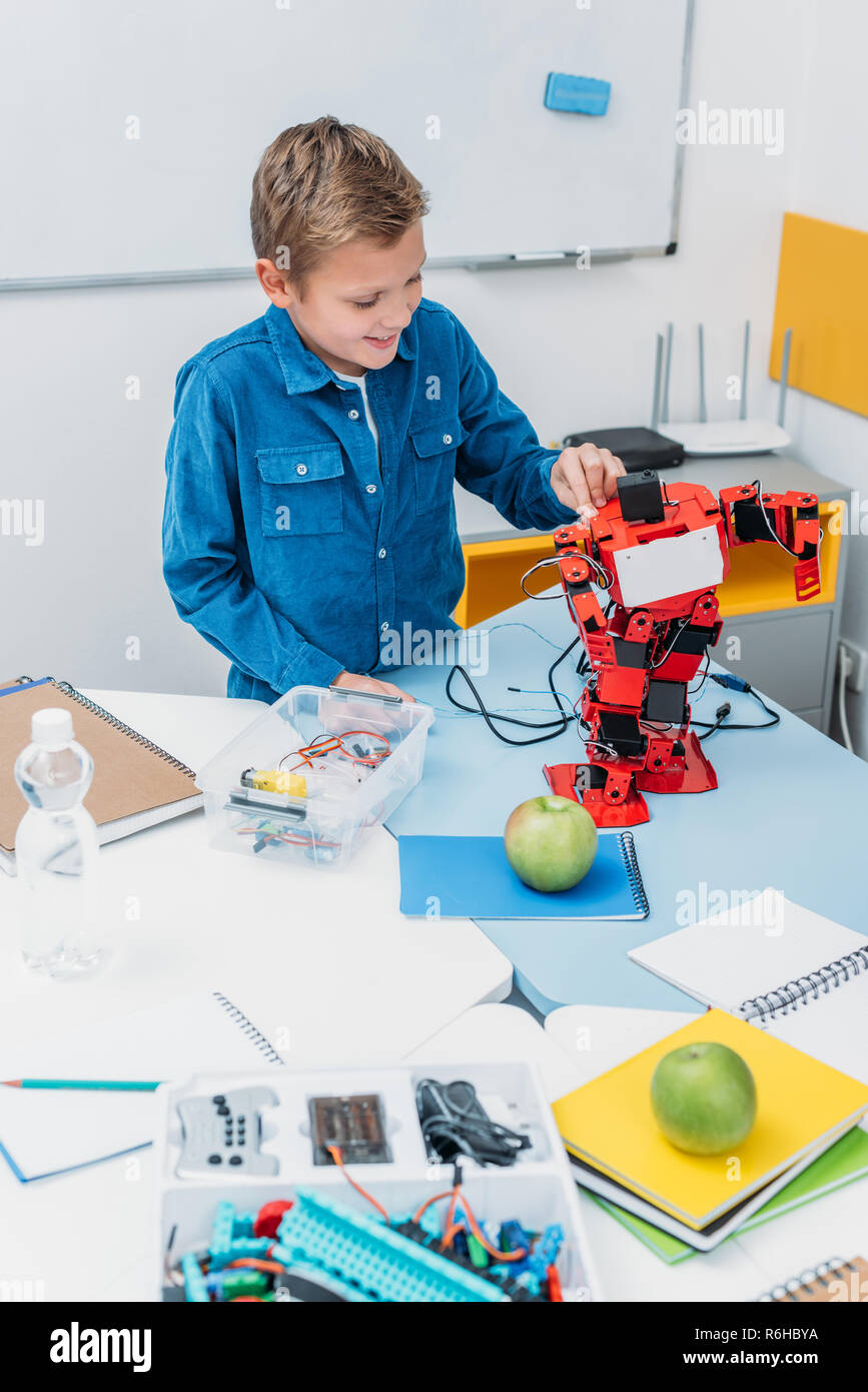happy schoolboy working on handmade robot model during STEM lesson ...