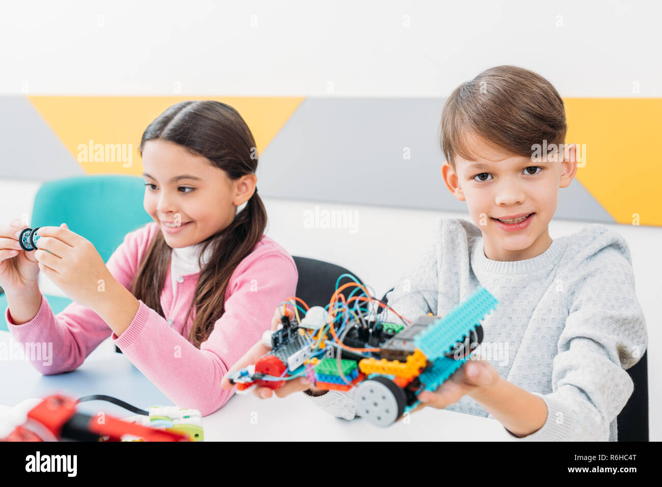 happy classmates holding robot model and working together on project ...