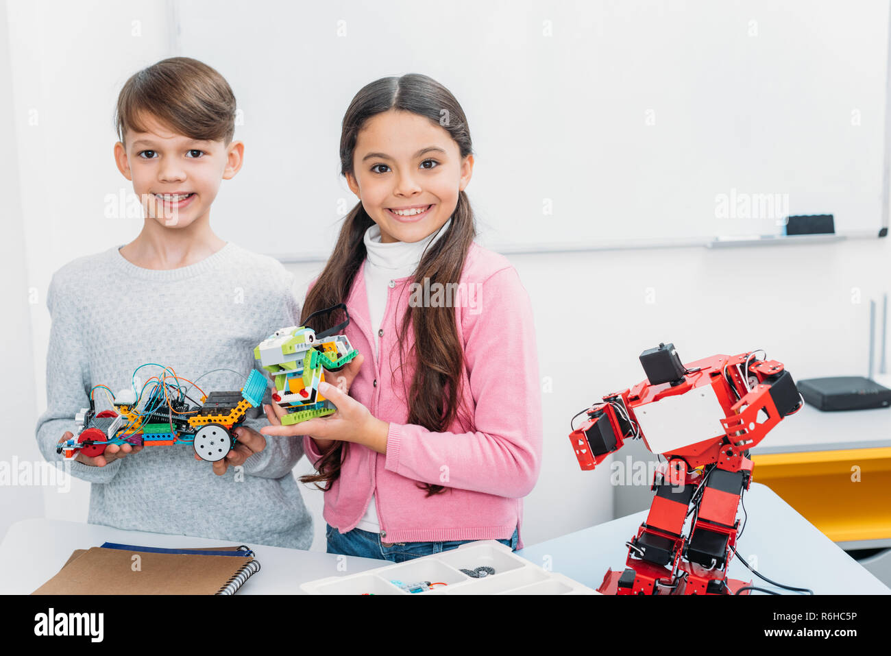 happy schoolchildren looking at camera and presenting handmade robot ...