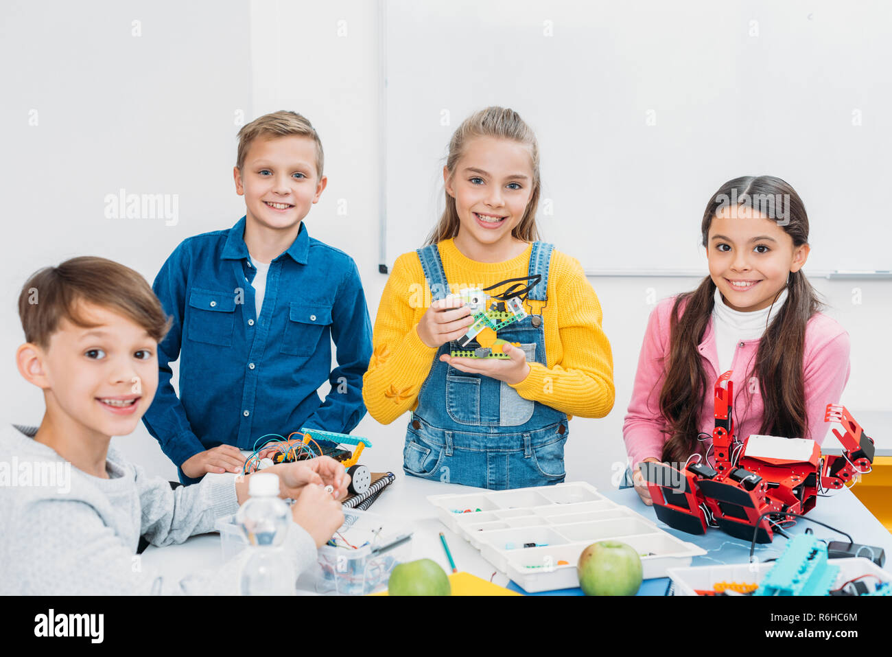 happy schoolchildren standing at desk with robots in stem class Stock ...