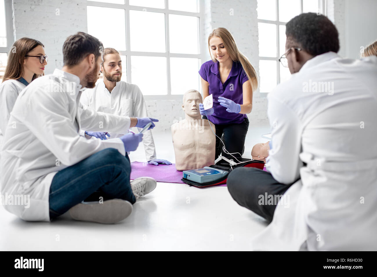 Group of young medics with instructor shows how to do defibrillation on ...