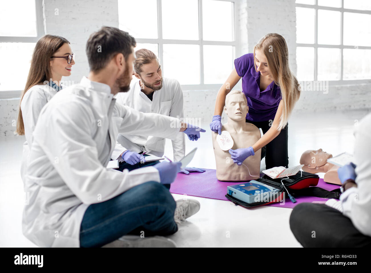 Group of young medics with instructor shows how to do defibrillation on ...