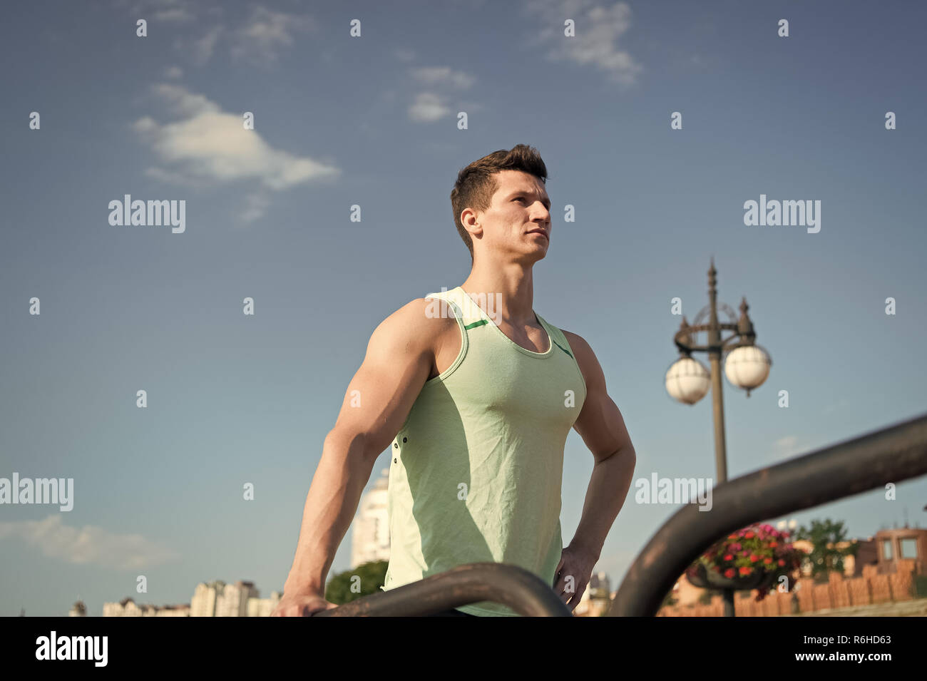 Man bodybuilder posing on blue sky. Athlete in green tshirt on sunny ...