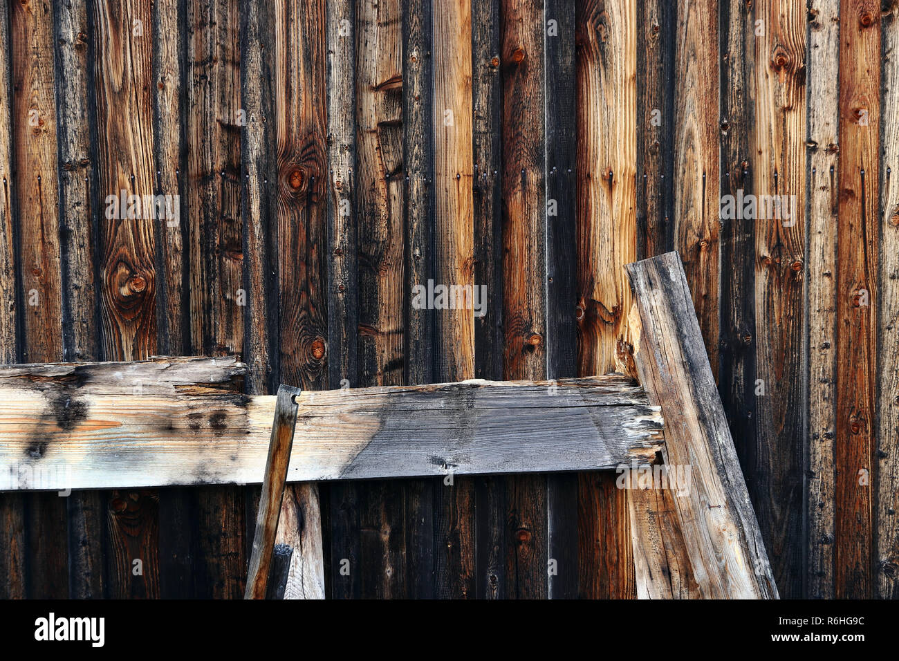 broken wood leans against a brown-black wooden wall. the wooden wall of ...