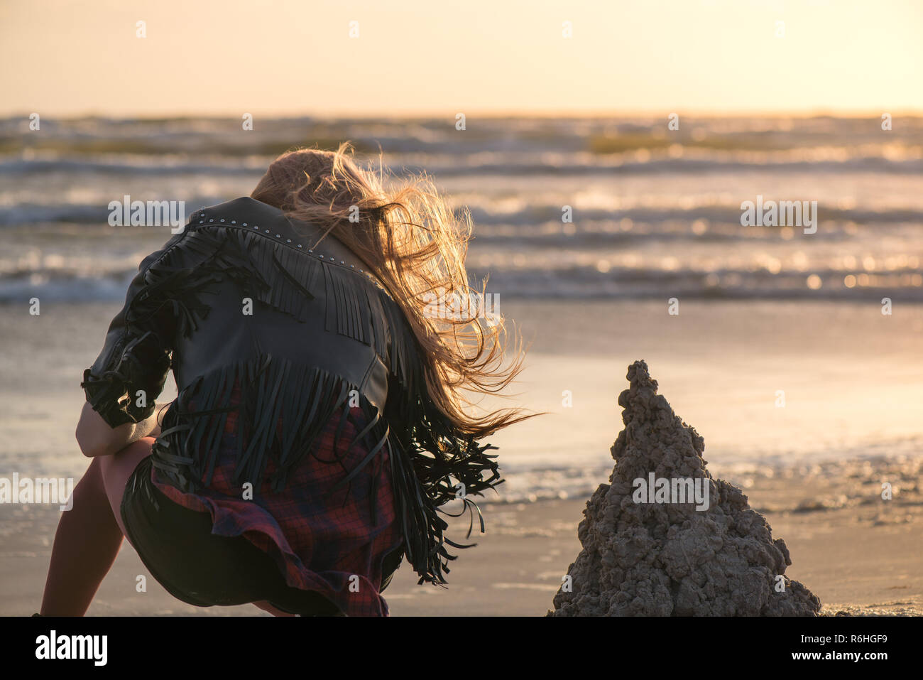 Young woman building and making sand castle next to sea. Calm, relaxing ...