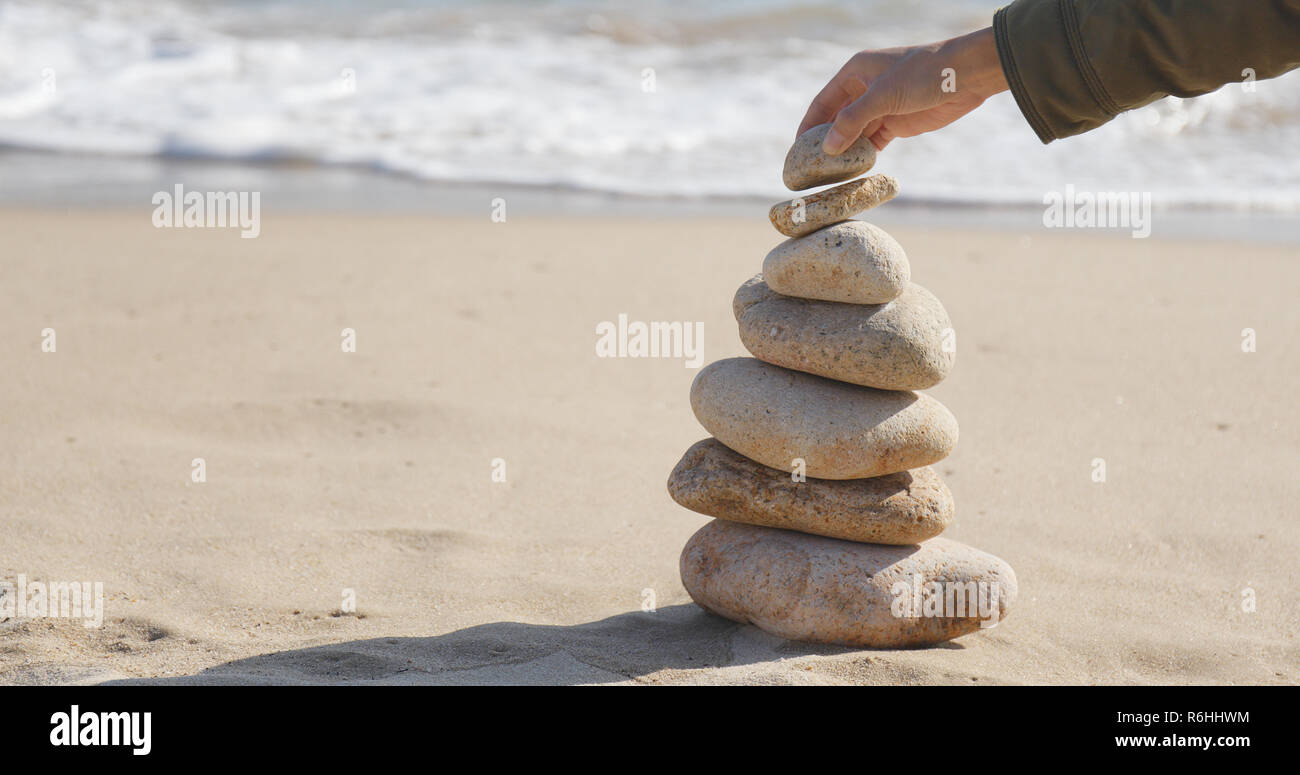 Hand putting the pebble stone on balance zen stock Stock Photo - Alamy