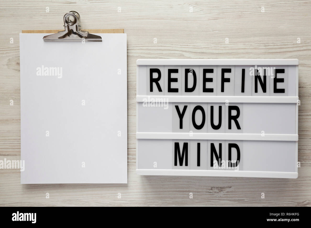 'Redefine your mind' words on modern board, noticepad over white wooden ...