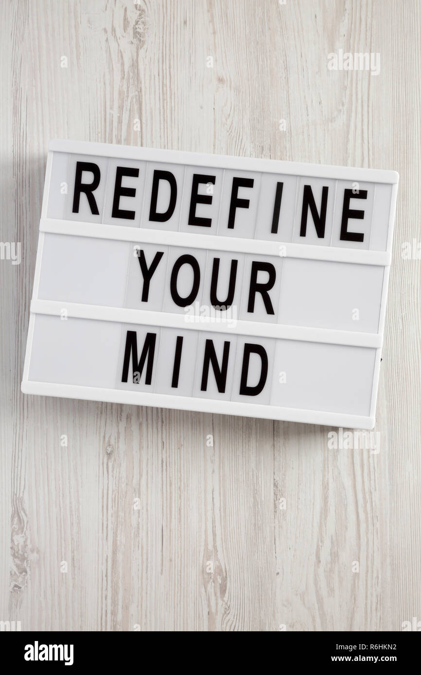 'Redefine your mind' words on lightbox over white wooden surface, top ...
