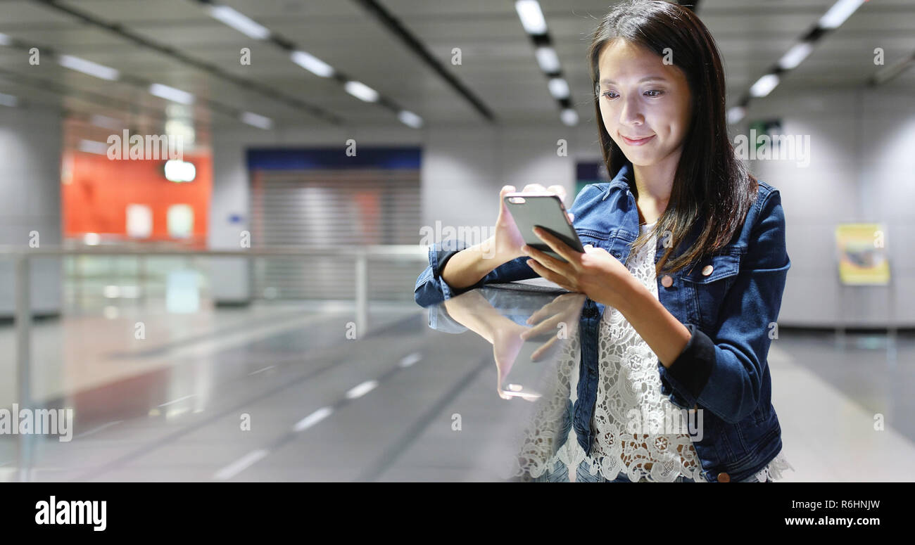 Woman using mobile phone in public station Stock Photo - Alamy