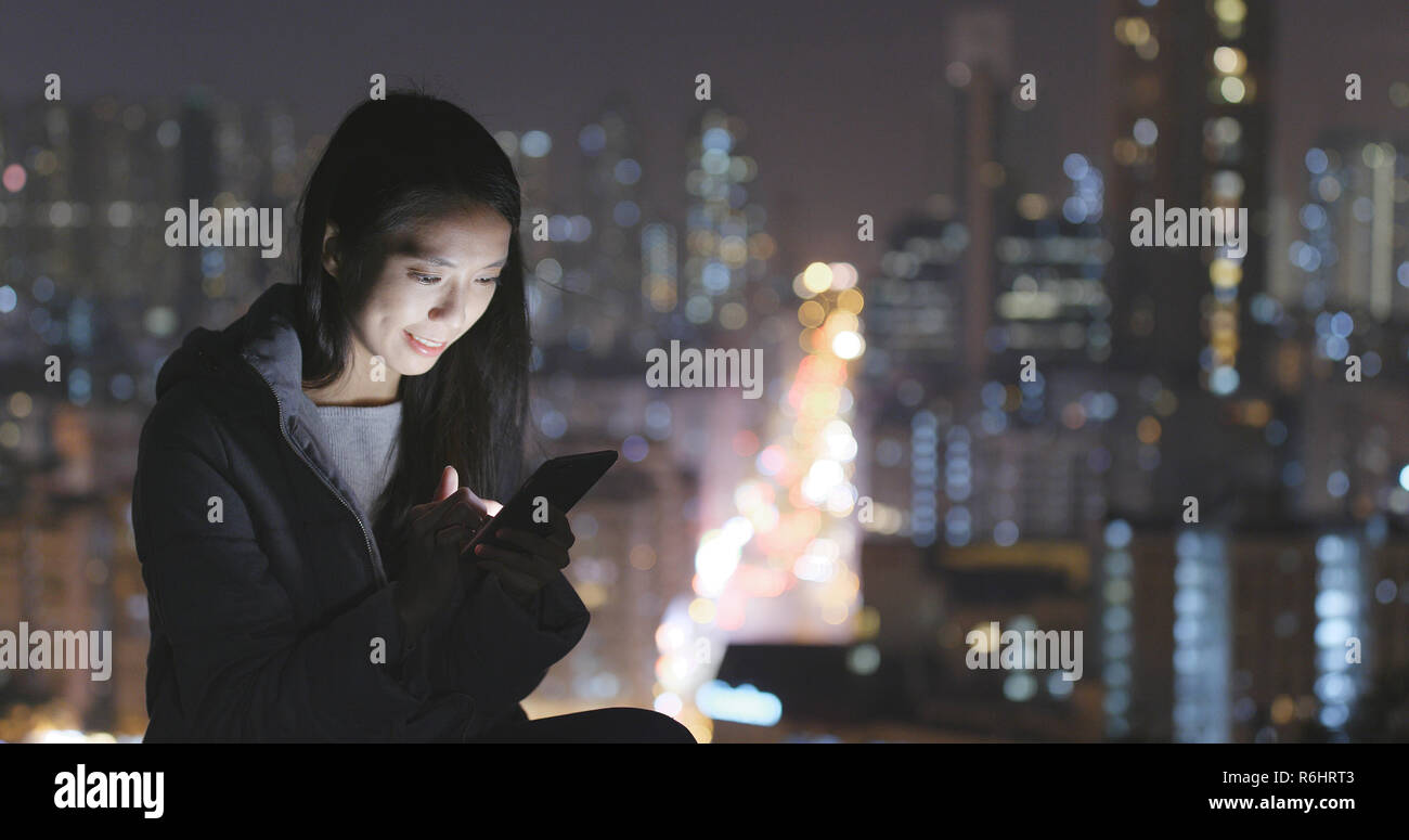 Woman use of mobile phone over city at night Stock Photo - Alamy