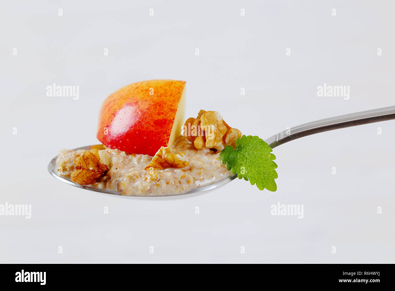 spoon of oatmeal porridge with apples and walnuts Stock Photo - Alamy