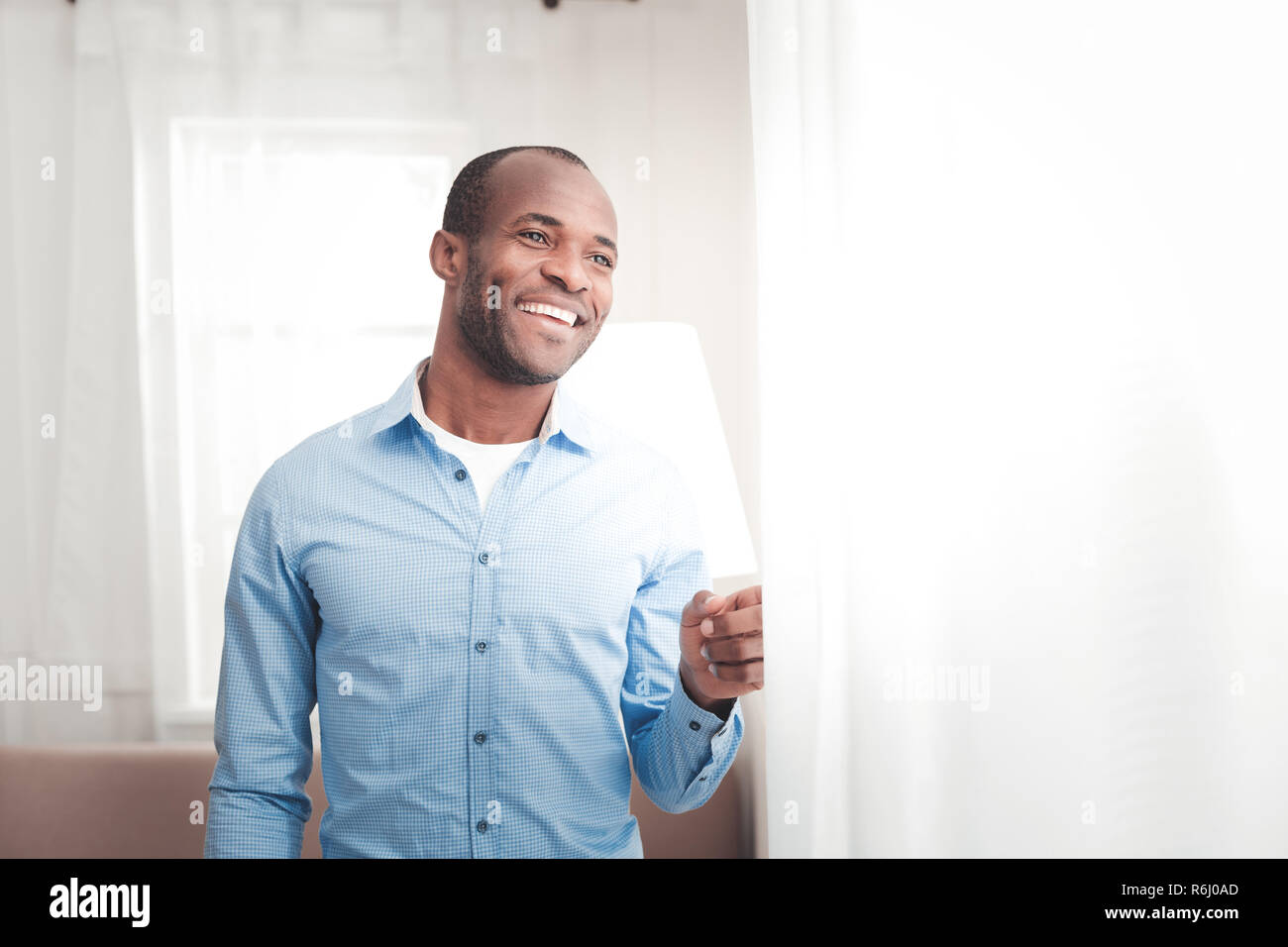 Happy cheerful man standing near the window Stock Photo - Alamy