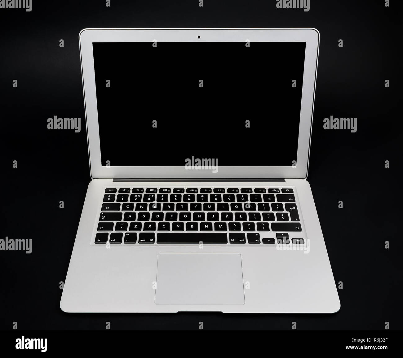 Laptop with black screen on black background, white aluminium body ...