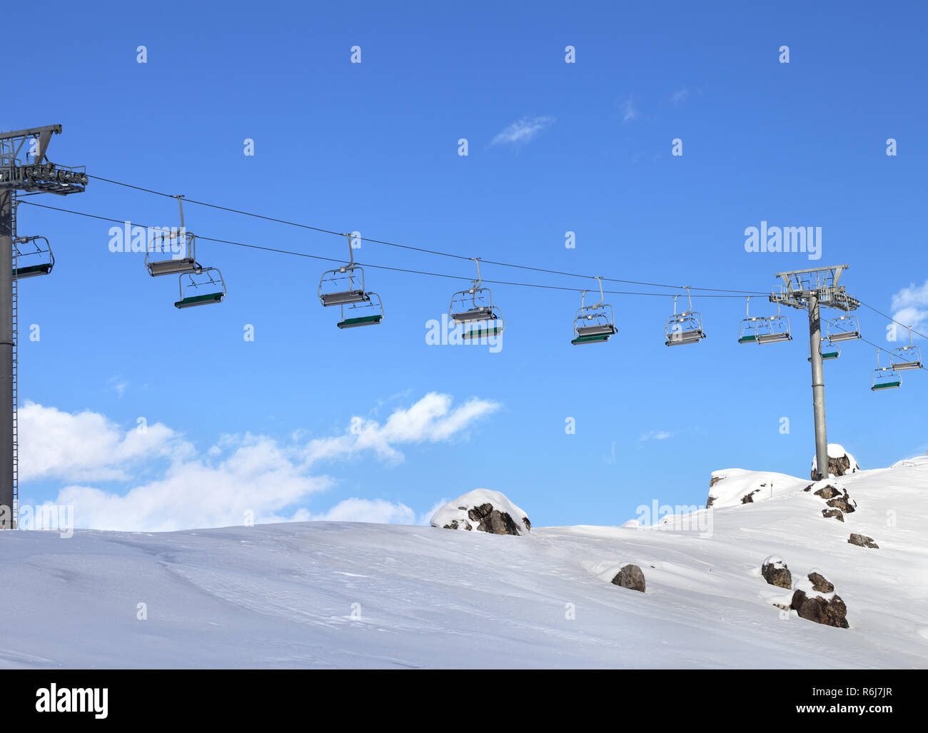Sunlight chair-lift and blue sky with clouds at ski resort on sun cold ...