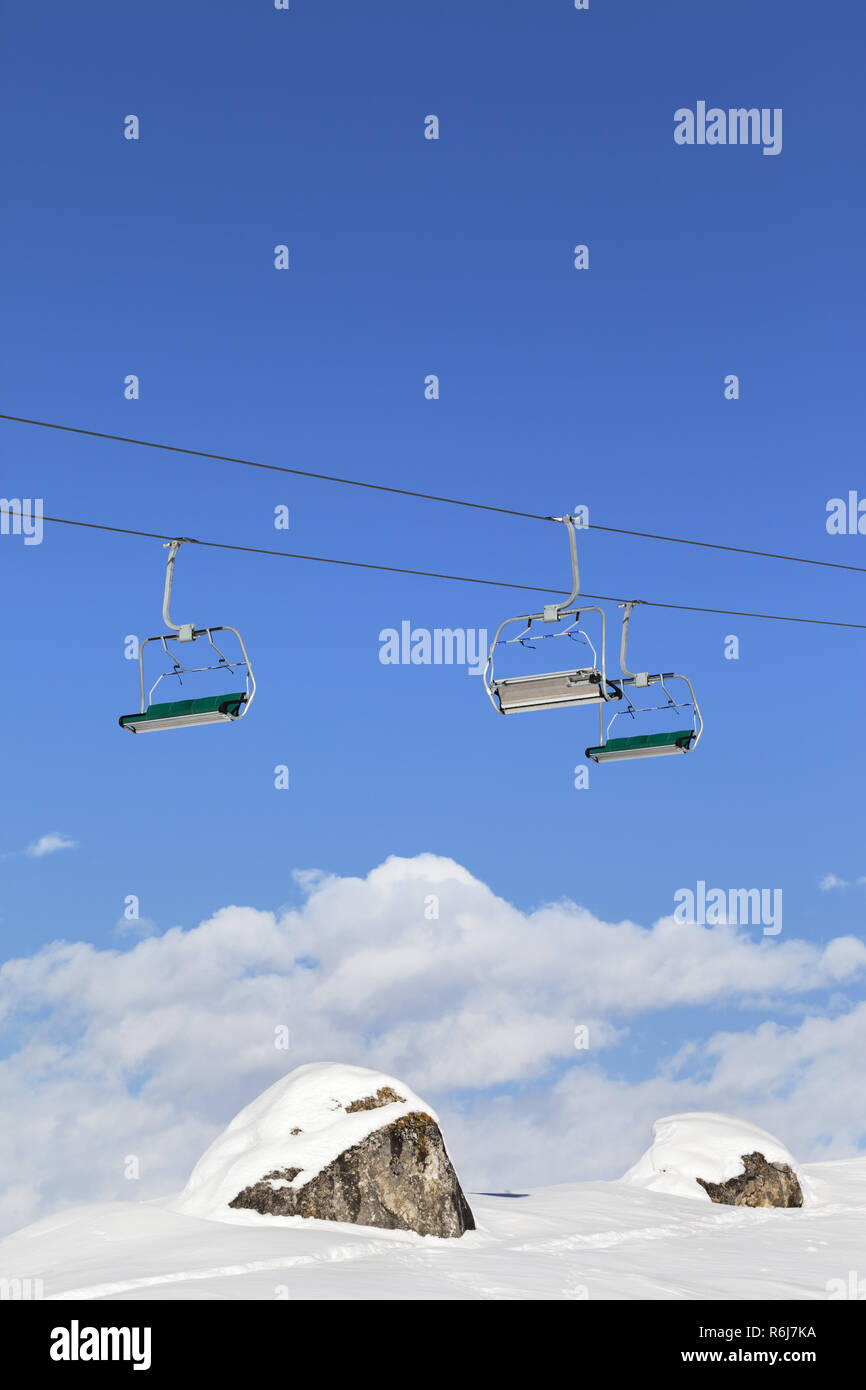 Sunlight chair-lift and blue sky with clouds at ski resort on sun cold ...