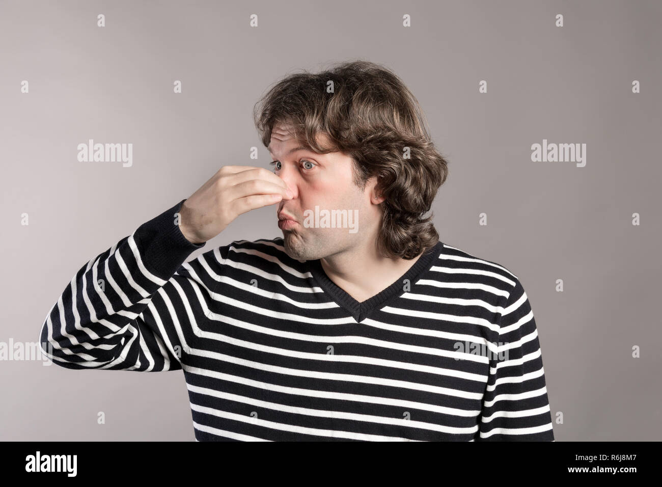 Young man disgust on his face, pinches his nose, something stinks, very ...
