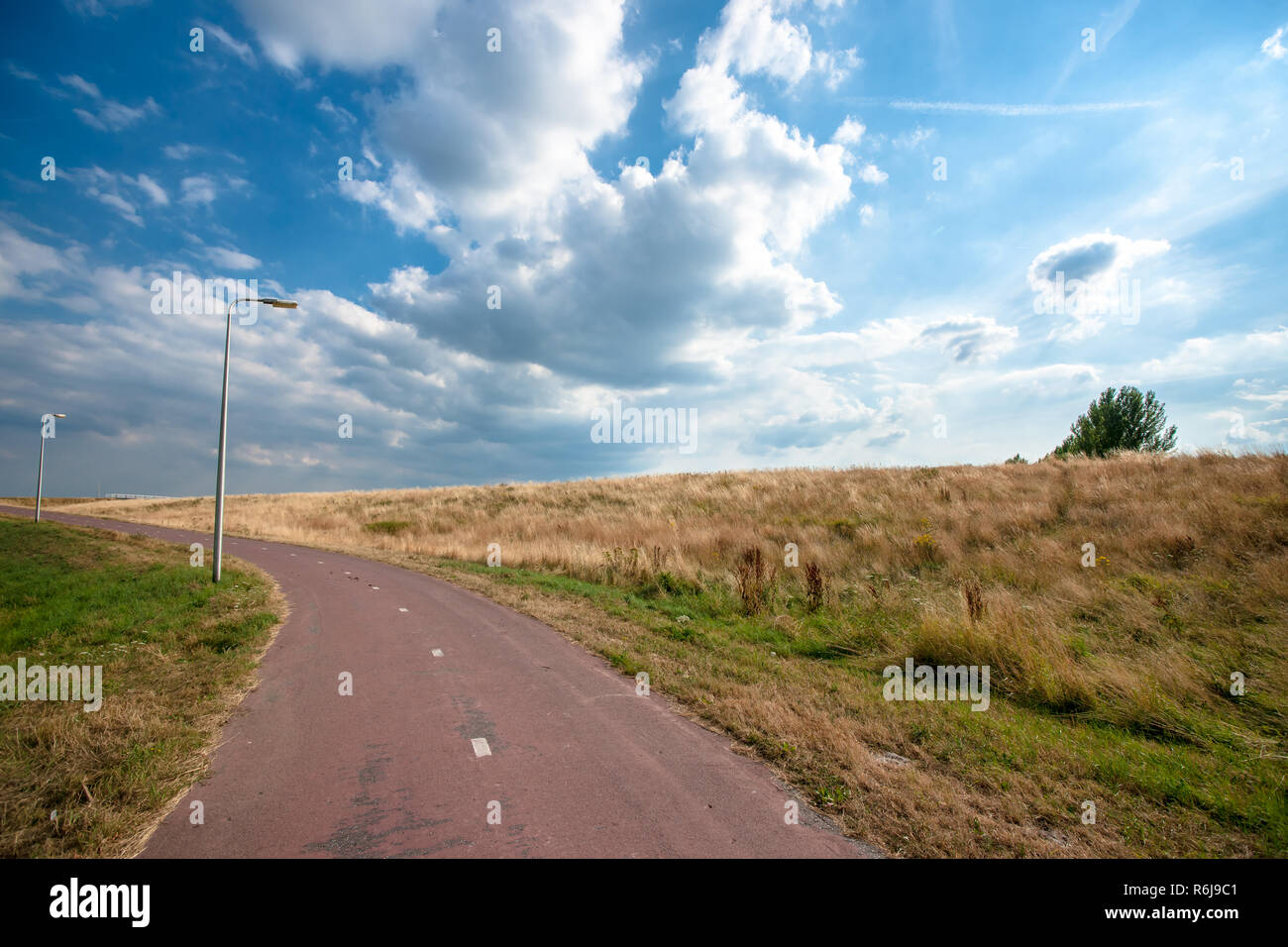 Paved hard stone road along dutch cultivated landscape. Blue skies ...
