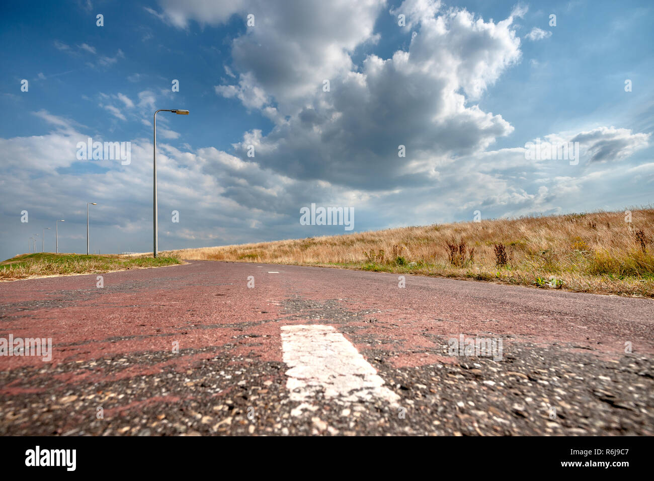 Paved hard stone road along dutch cultivated landscape. Blue skies ...
