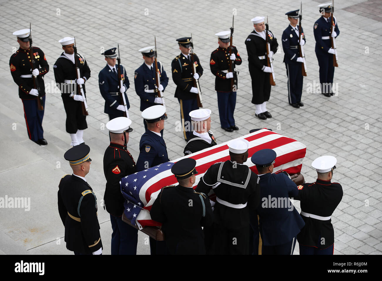 A U.S. military honor guard team carries the flag draped casket of ...