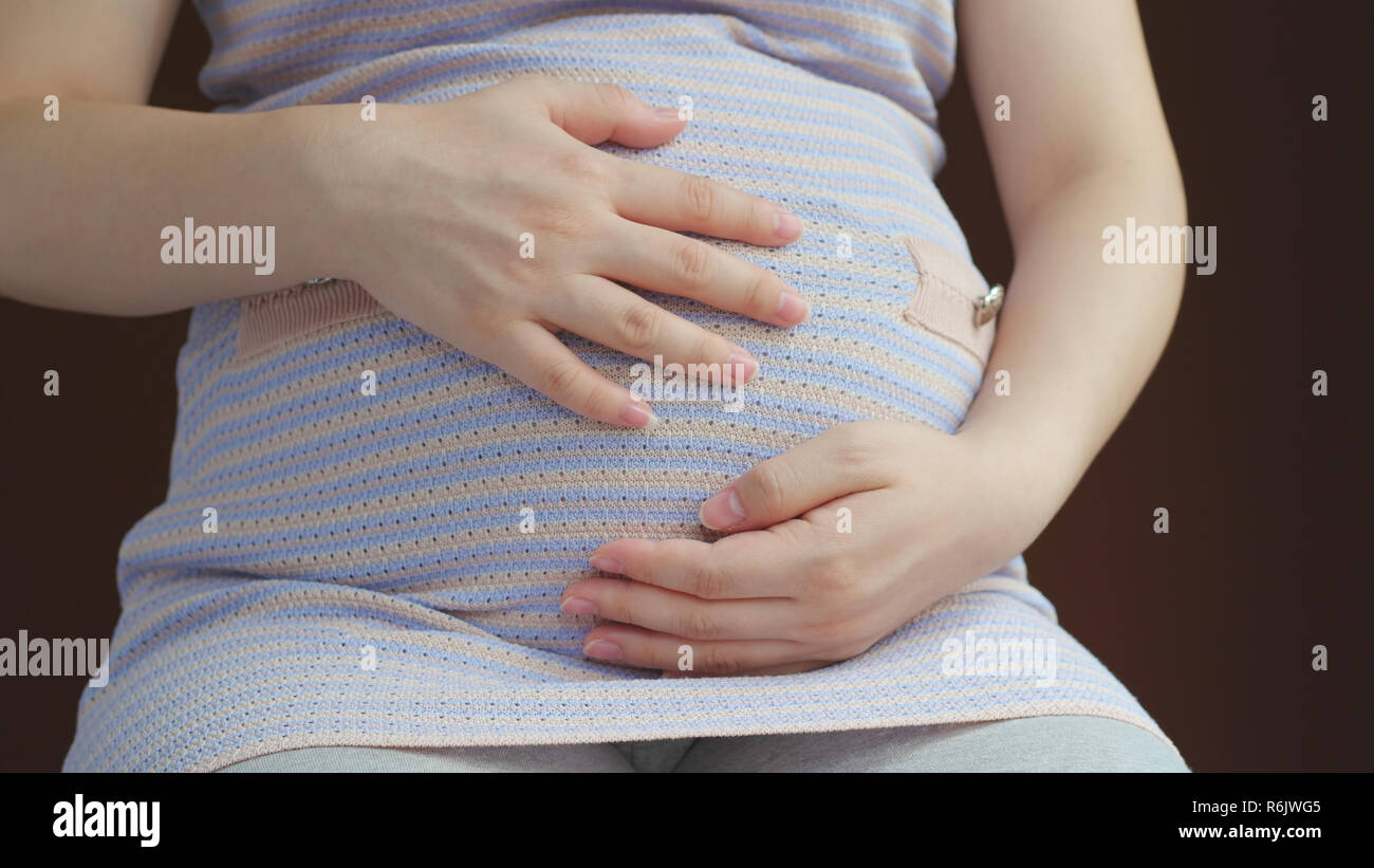 Woman caressing her belly Stock Photo - Alamy