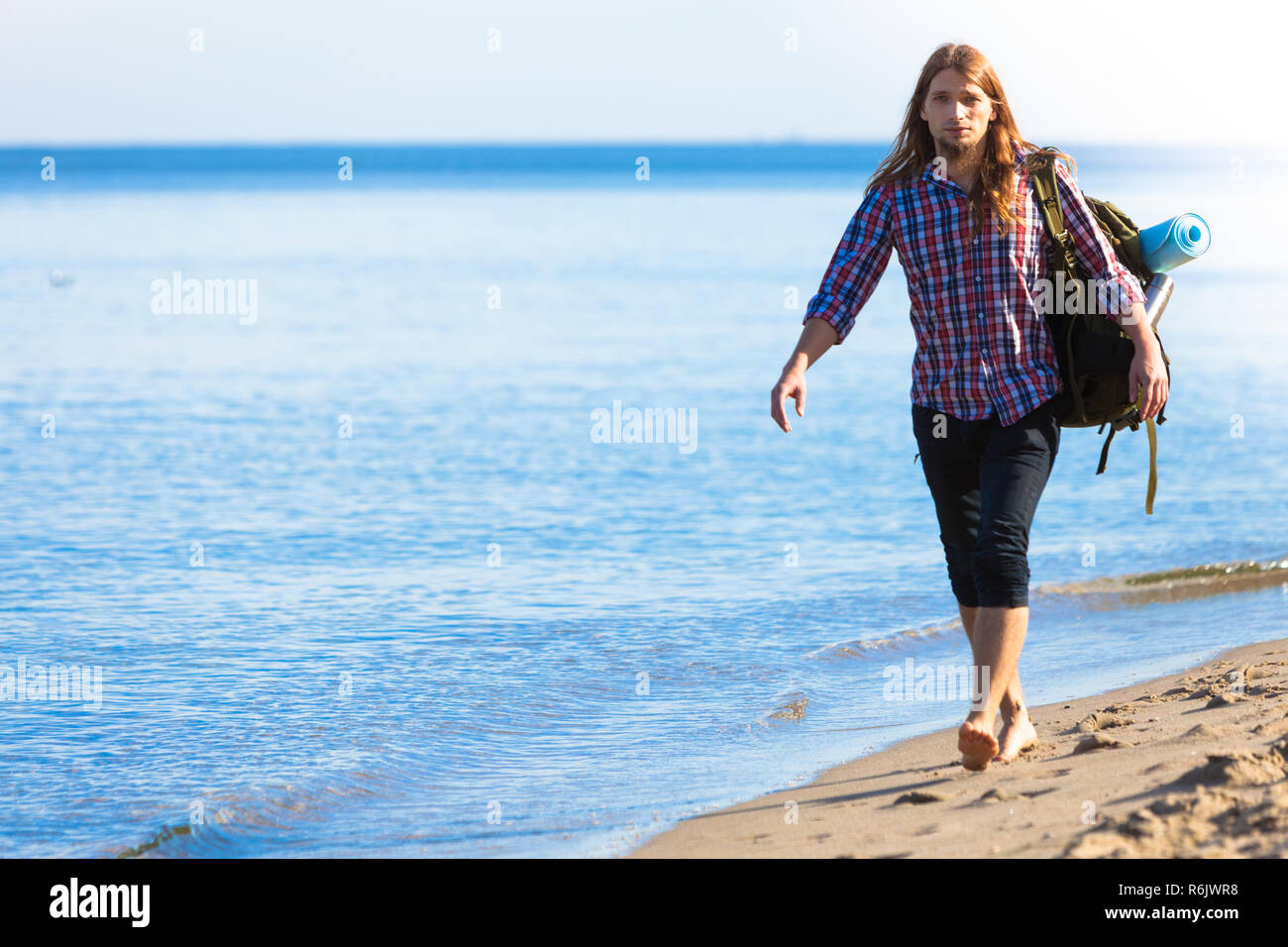 Man hiker backpacker walking with backpack on sea shore at sunny day ...