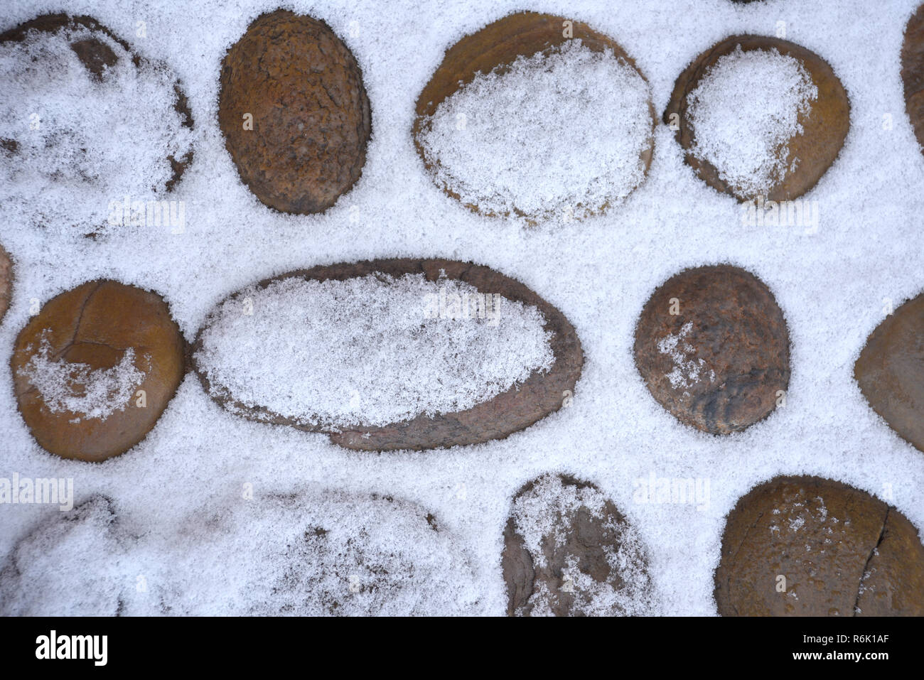 A light snowfall on round river rocks Stock Photo - Alamy