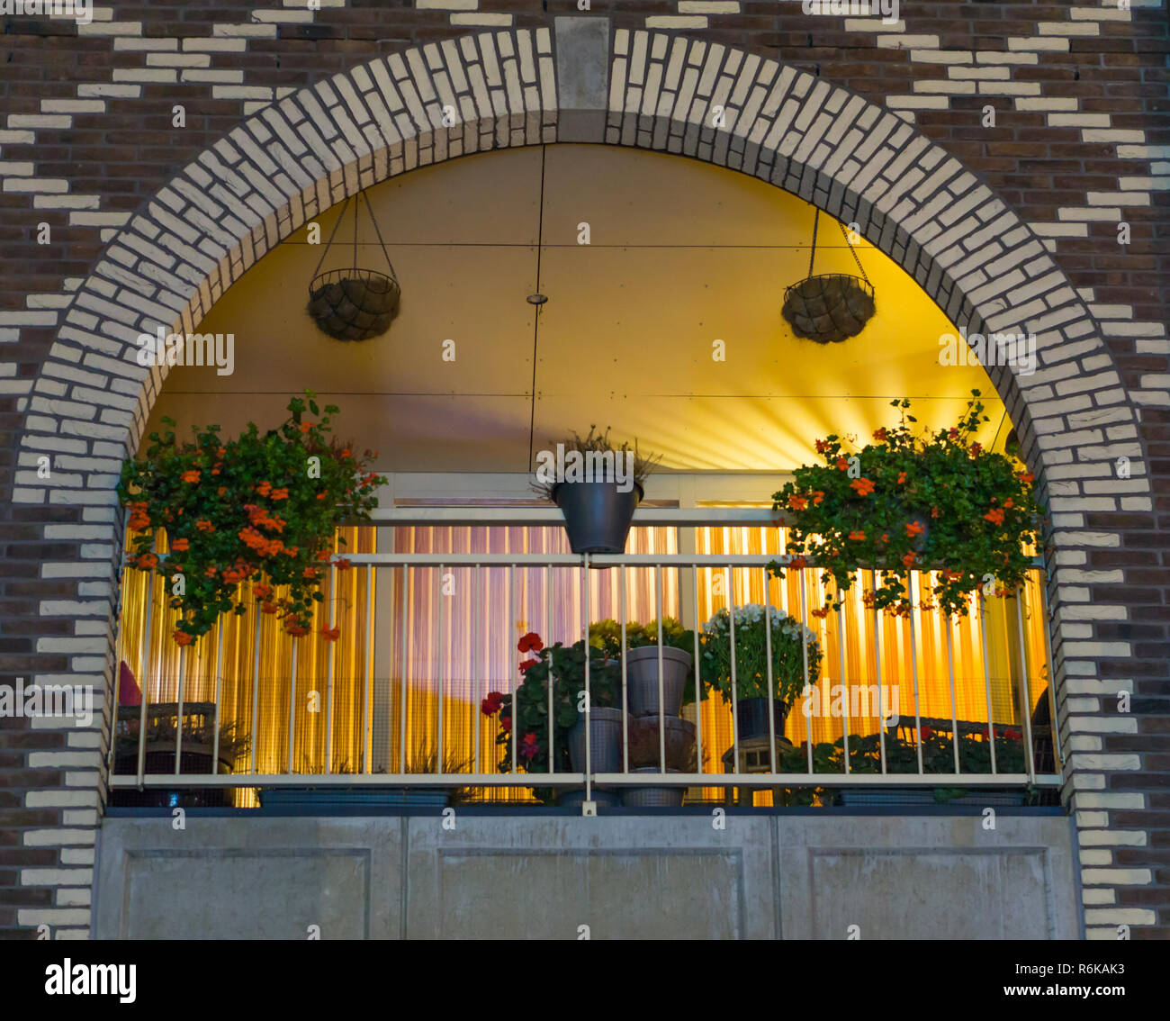 beautiful arched dutch balcony decorated with flowers at night, modern ...