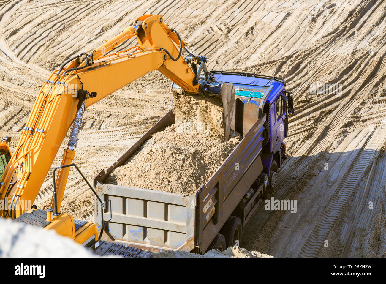 Work of the excavator and truck at a sand quarry. Excavator loading ...