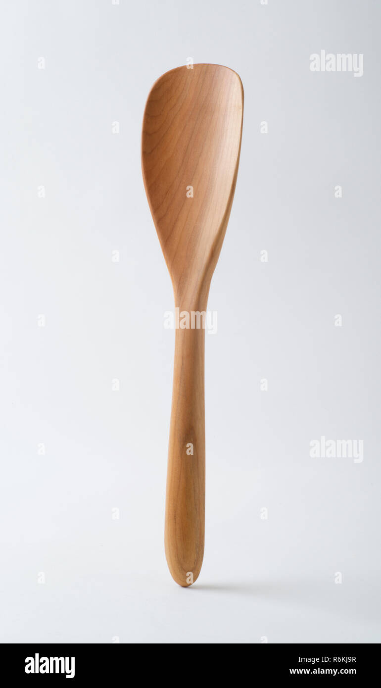 Handmade wooden spatula standing vertically on a white background. This ...