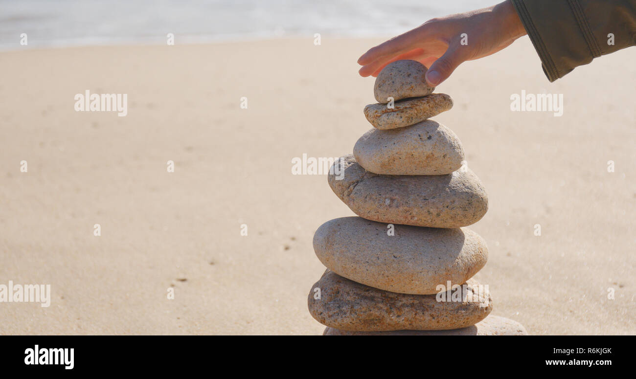 Hand putting the pebble stone on balance zen stock Stock Photo - Alamy