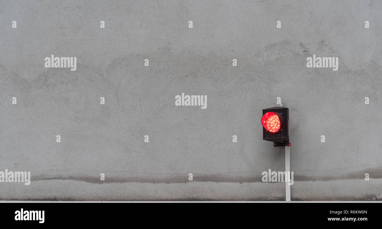 The traffic light shows red on the gray facade Stock Photo - Alamy