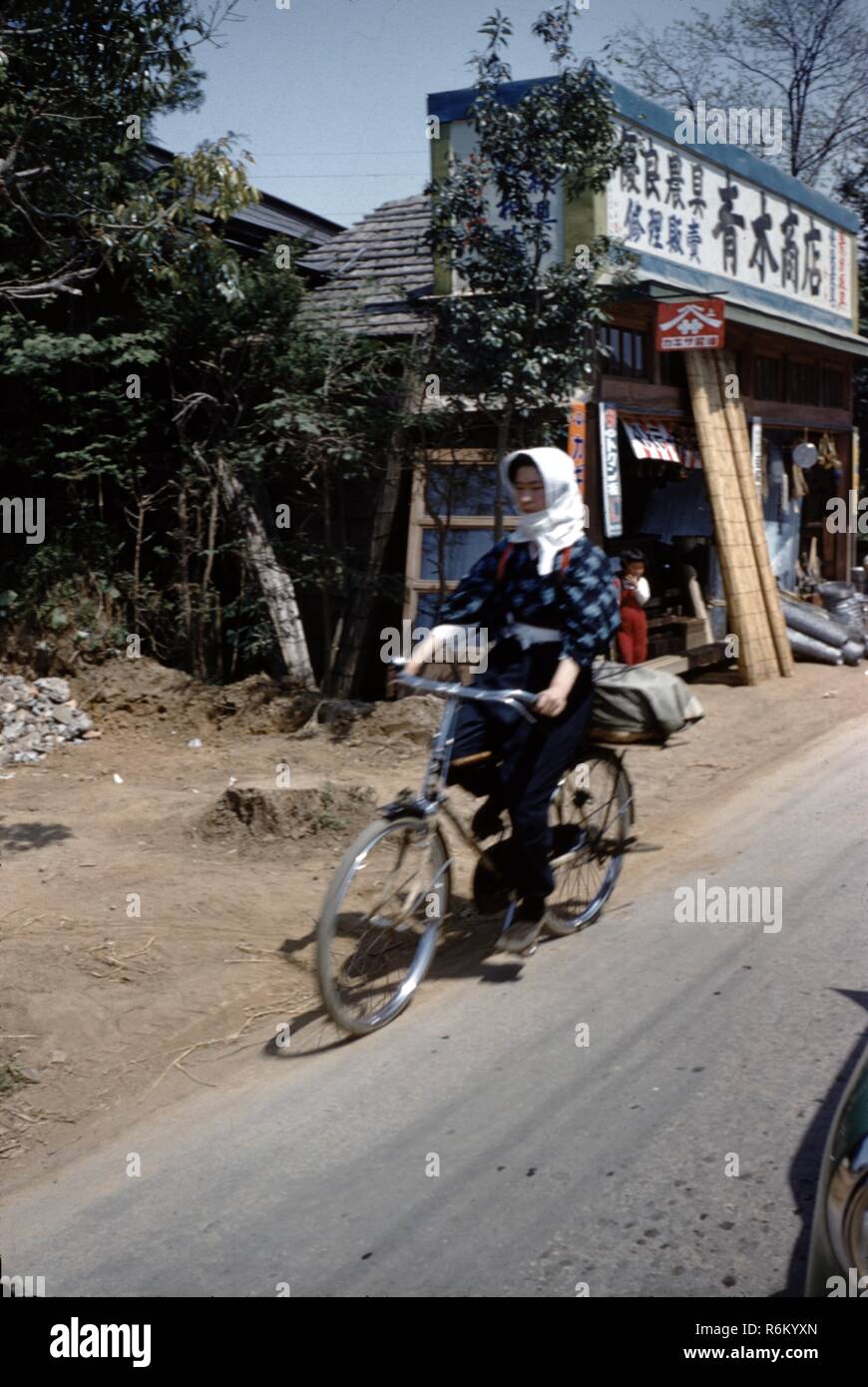A woman wearing traditional Japanese clothing rides a bicycle quickly ...
