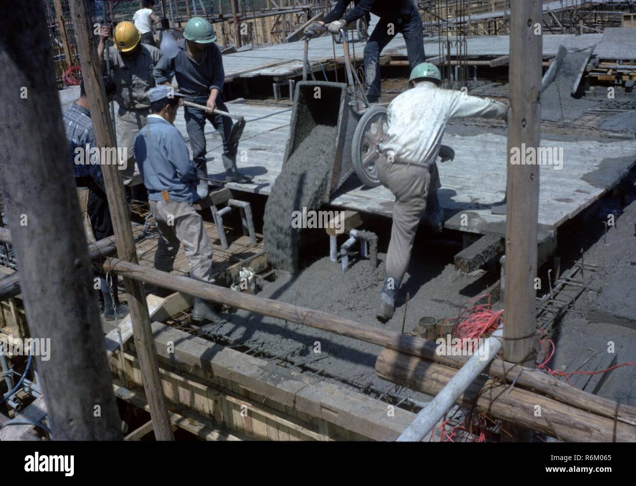 Workers pouring concrete while laying the foundation of a building at a ...