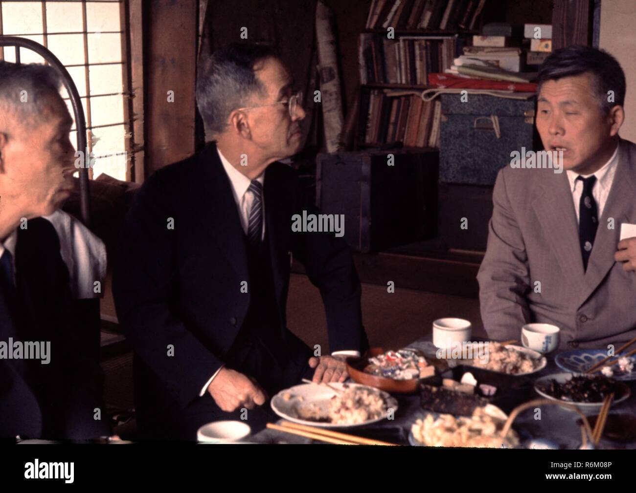 Three mature Japanese men wearing suits eat a traditional meal while ...