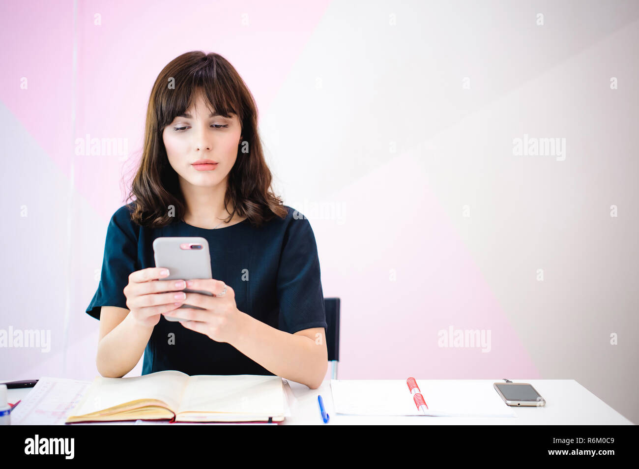 Portrait of a beautiful business woman making notes in a smartphone ...