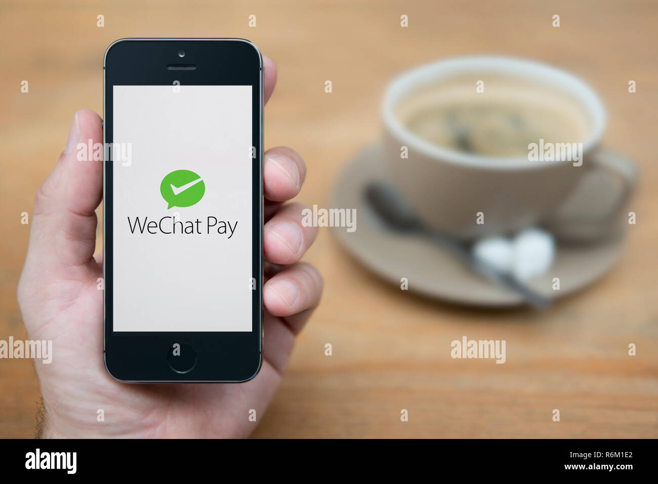 A man looks at his iPhone which displays the WeChat Pay logo (Editorial ...
