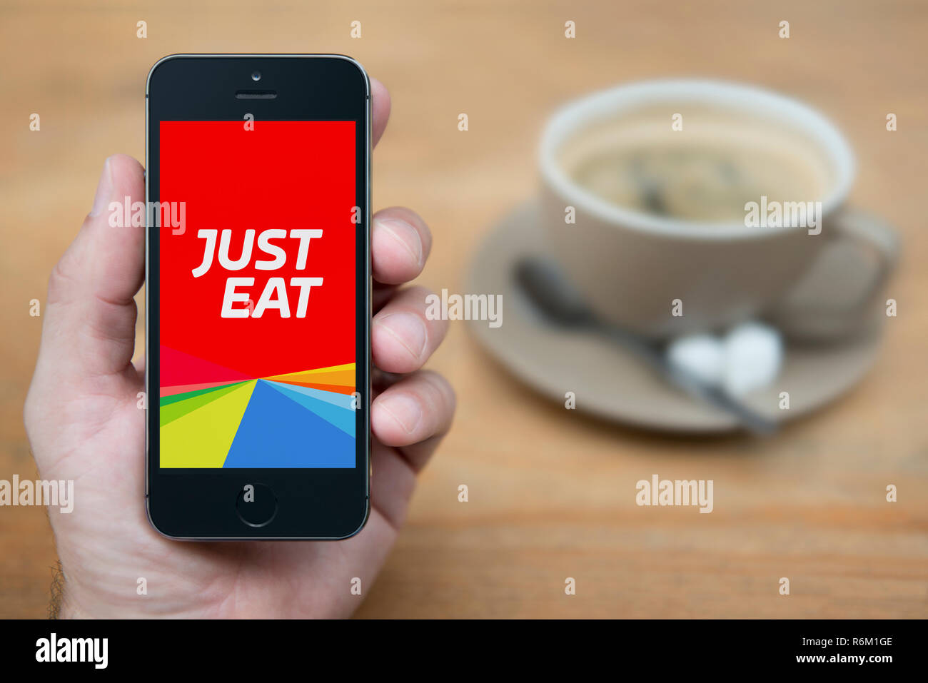 A man looks at his iPhone which displays the Just Eat logo (Editorial ...