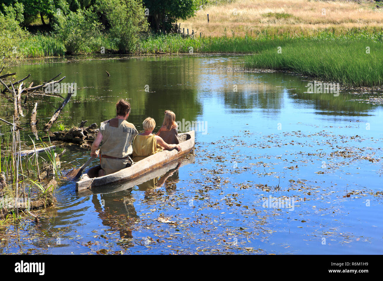 An Iron Age family in a wooden canoe paddeling across the water at The ...