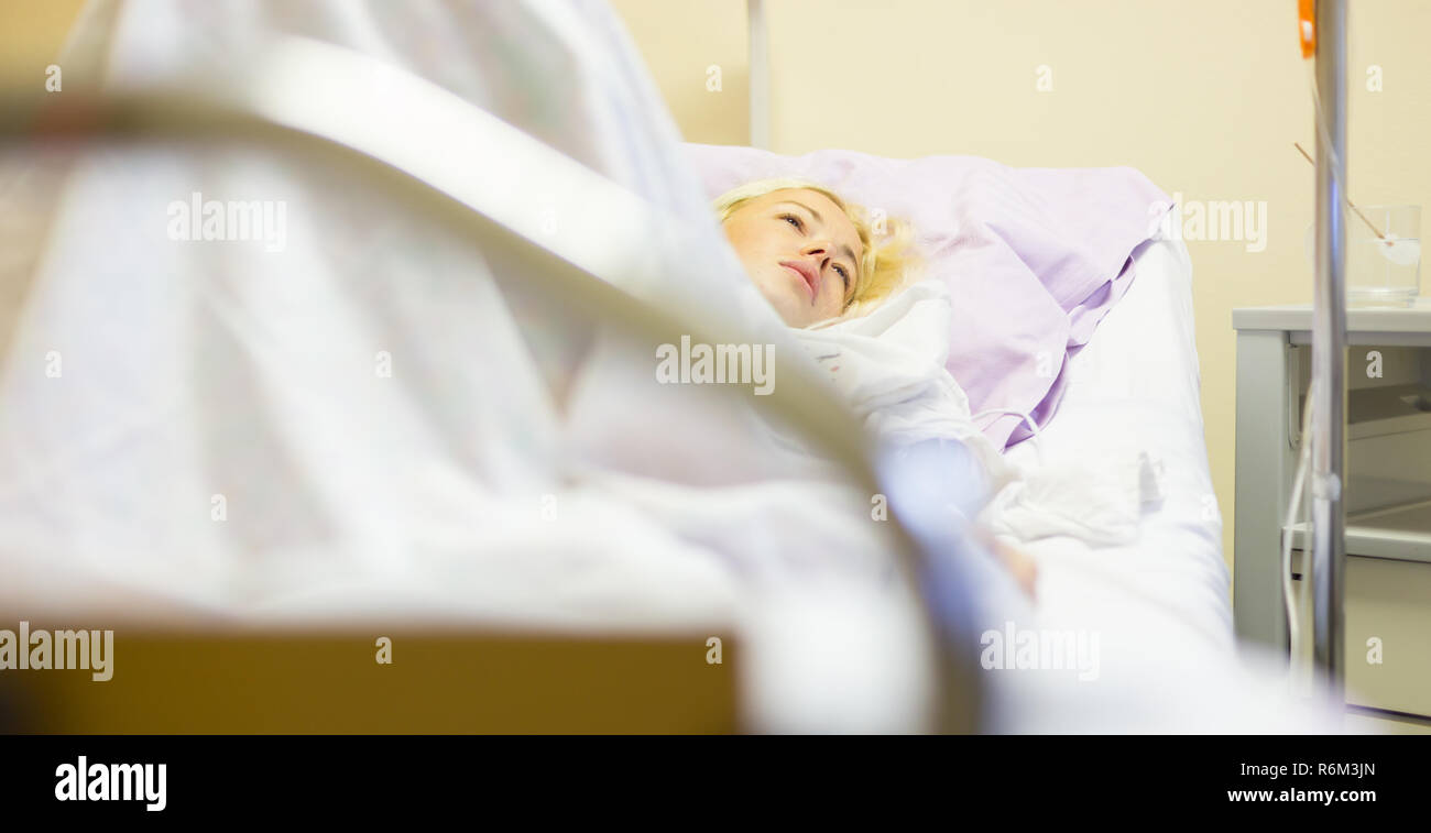 Bedridden female patient recovering after surgery in hospital care ...