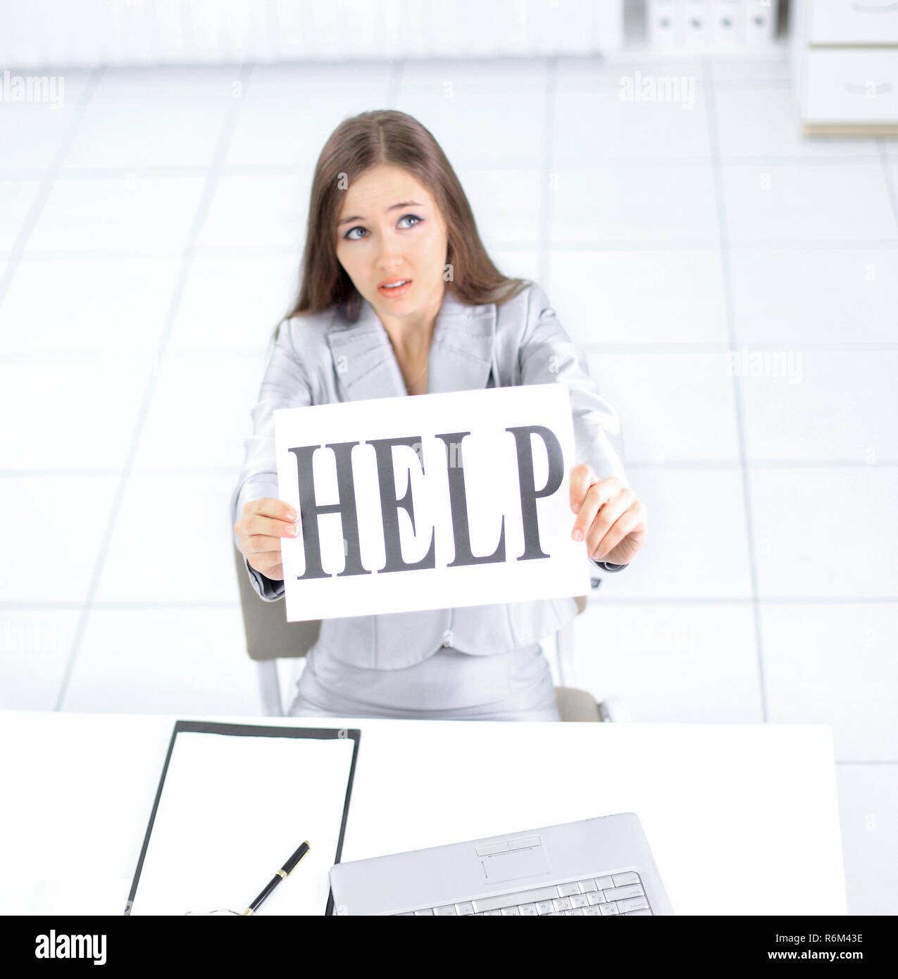 business woman holding a sign saying help ,sitting behind a Desk Stock ...