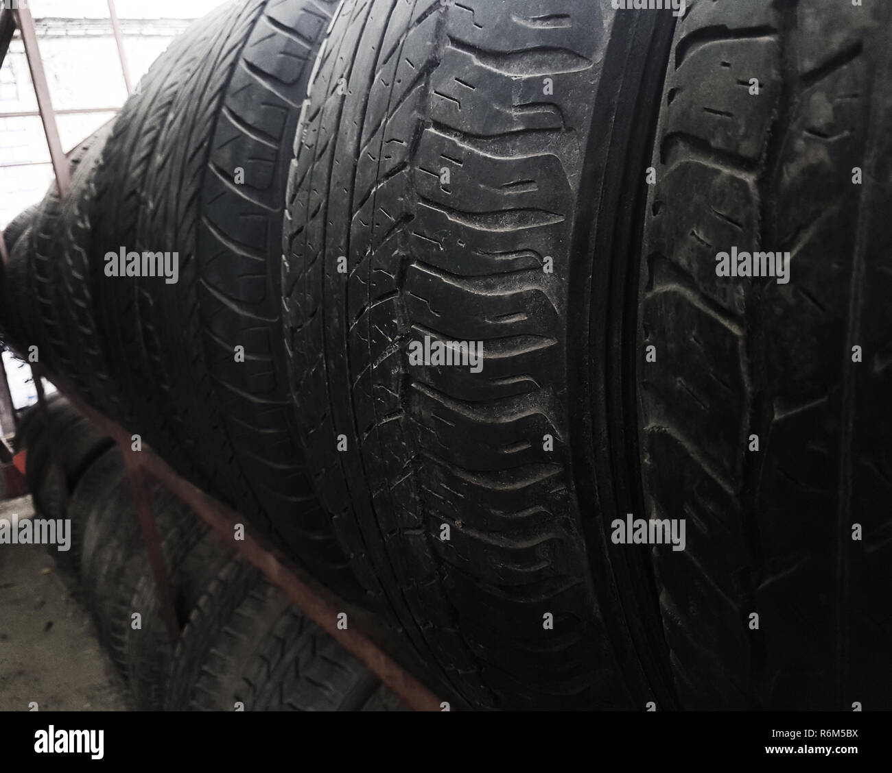 row of worn tires on a rack in the garage Stock Photo - Alamy