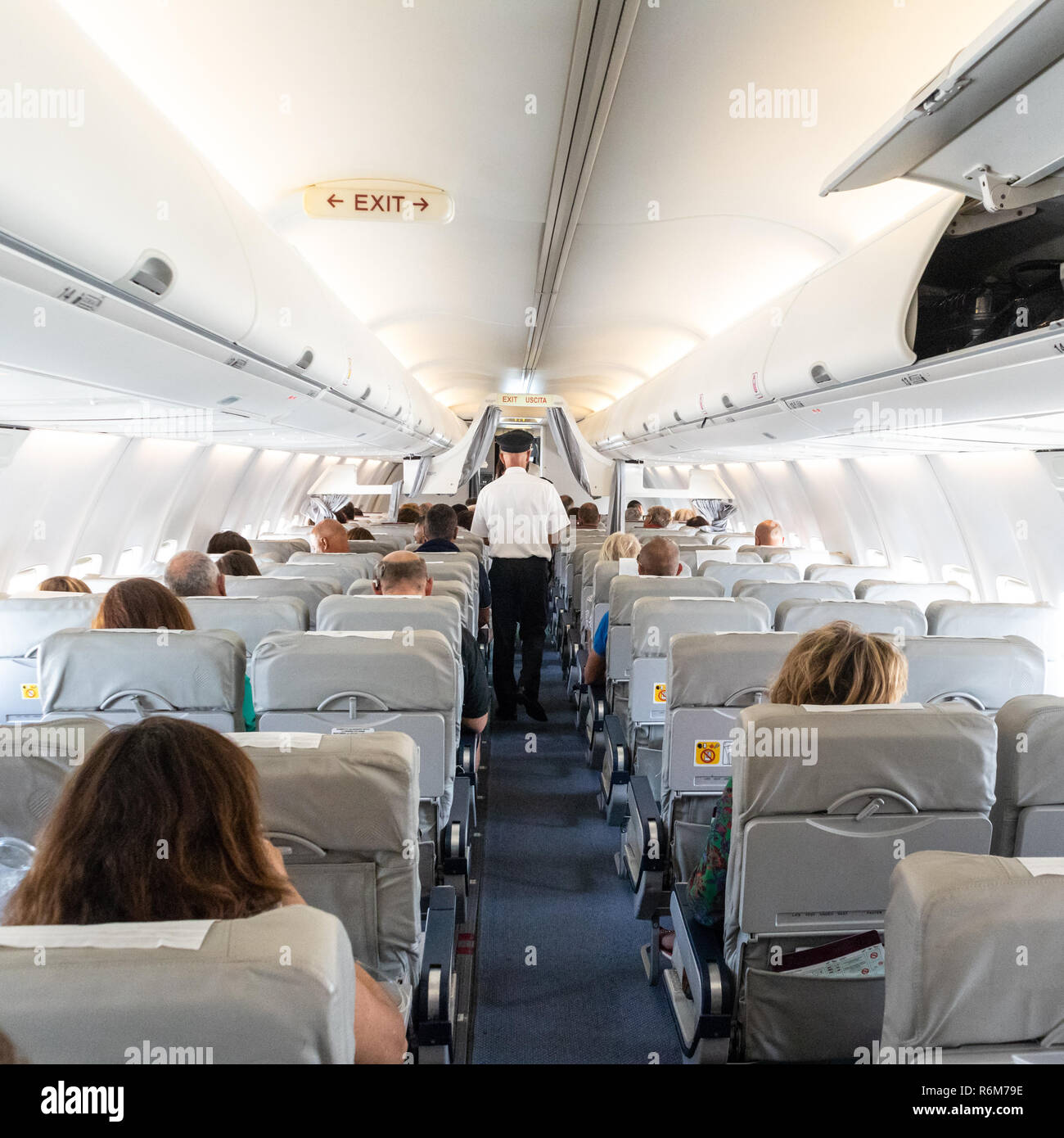 Interior of commercial airplane with passengers on their seats during ...