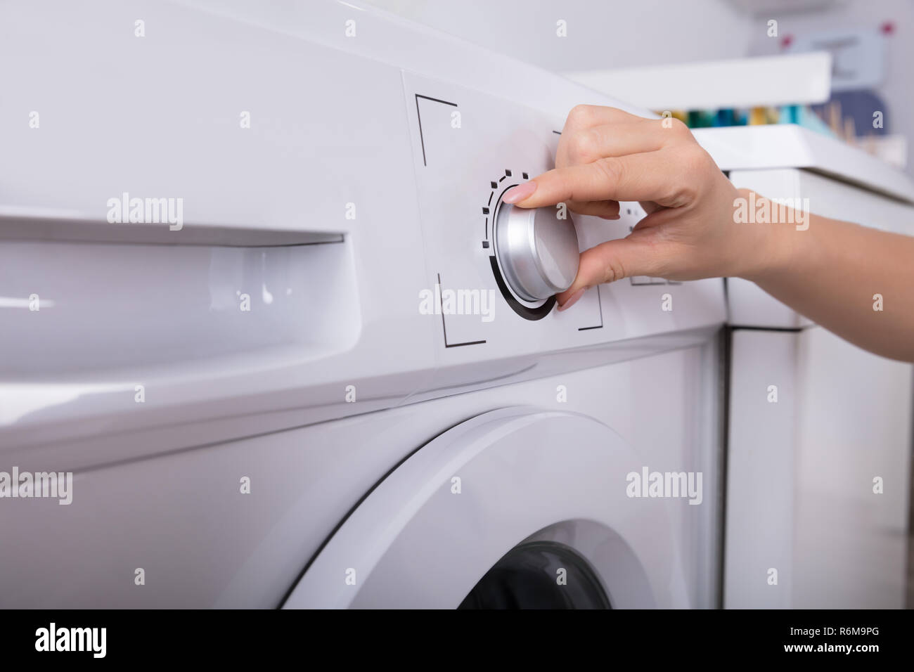 Woman Turning Button Of Washing Machine Stock Photo - Alamy